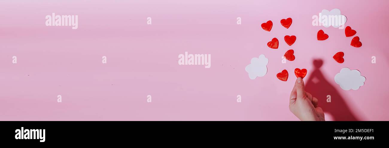 A small textile heart in his hands casting a shadow on a pink ...