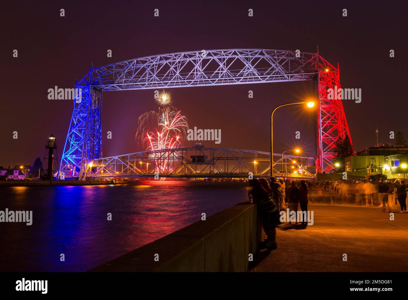 Fireworks behind an aerial lift bridge lit up in red, white, and blue ...