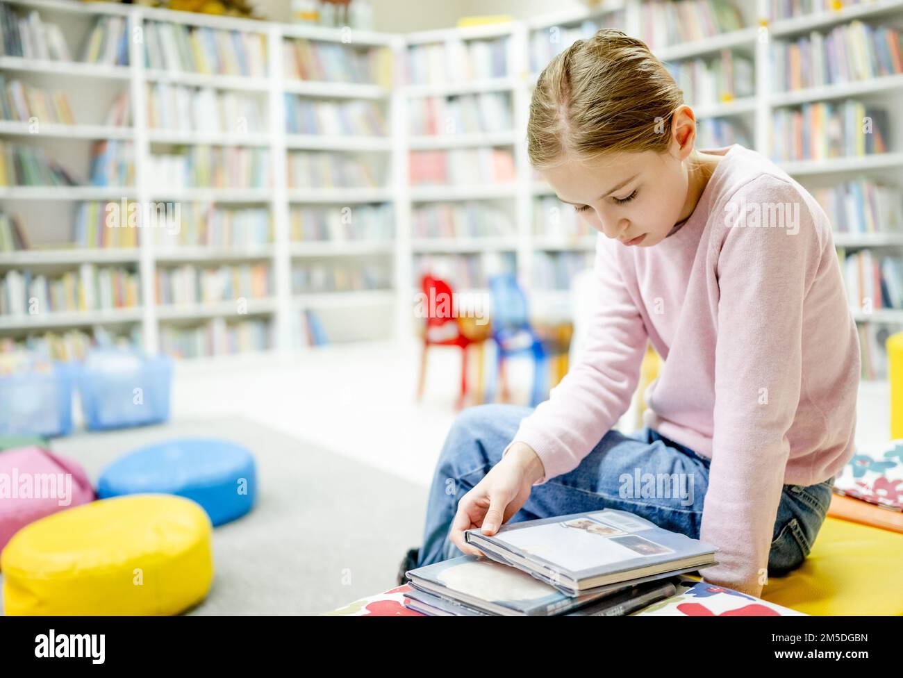 Pretty girl child reading book in library Stock Photo - Alamy