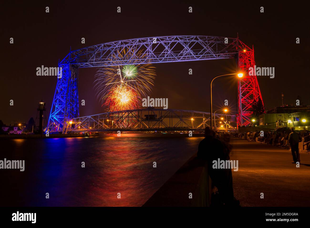 Fireworks behind an aerial lift bridge lit up in red, white, and blue ...