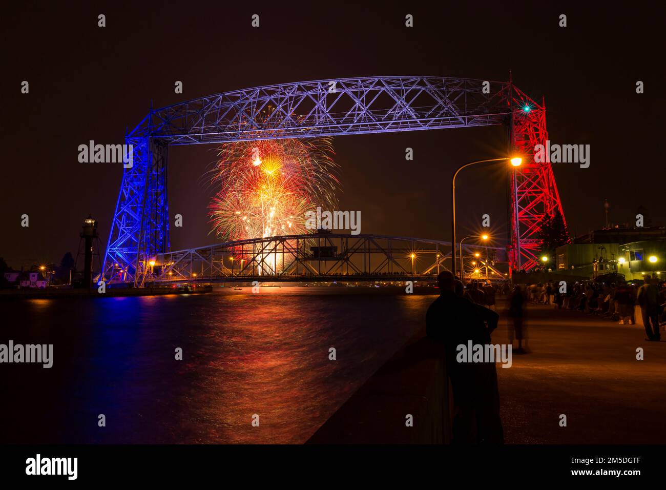 Fireworks behind an aerial lift bridge lit up in red, white, and blue ...