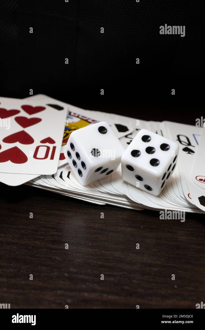 A vertical closeup shot of gambling dice and playing cards on a wooden ...