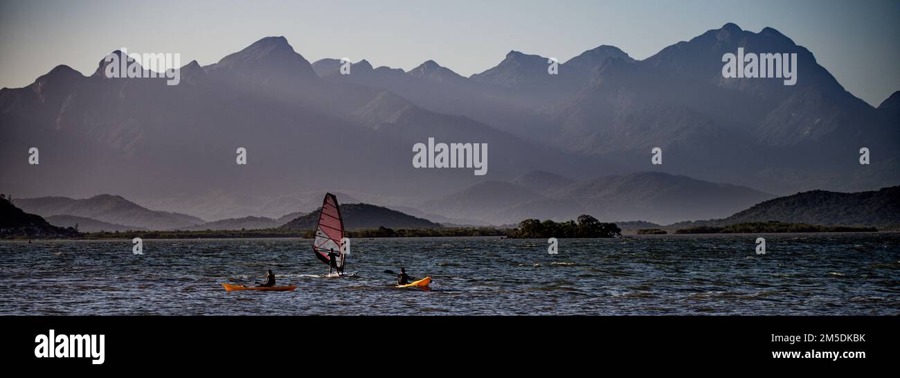 A panoramic of people on rowing boats and windsurfing on the seascape ...