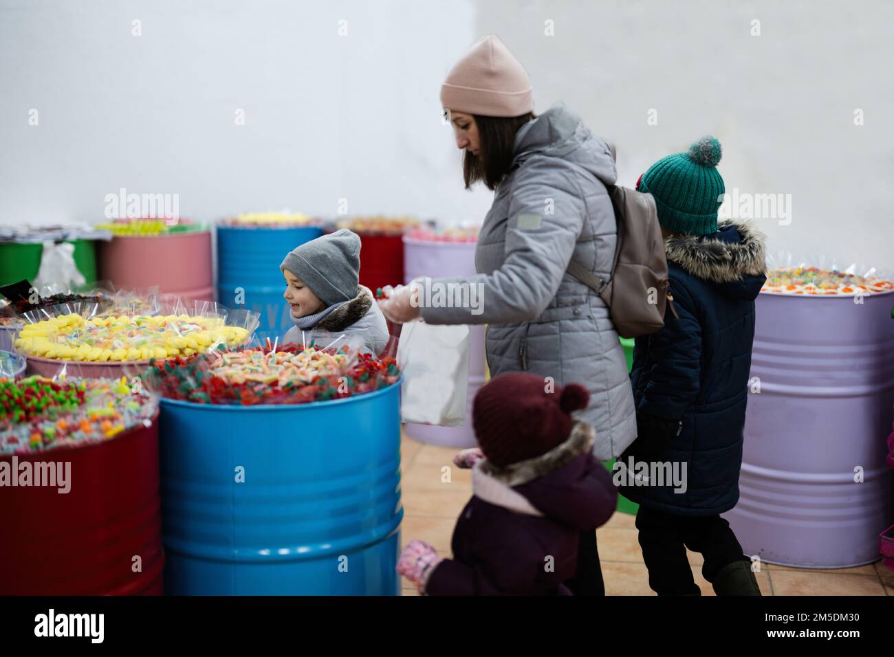 Happy little kids with mother in a candy store chooses sweets ...