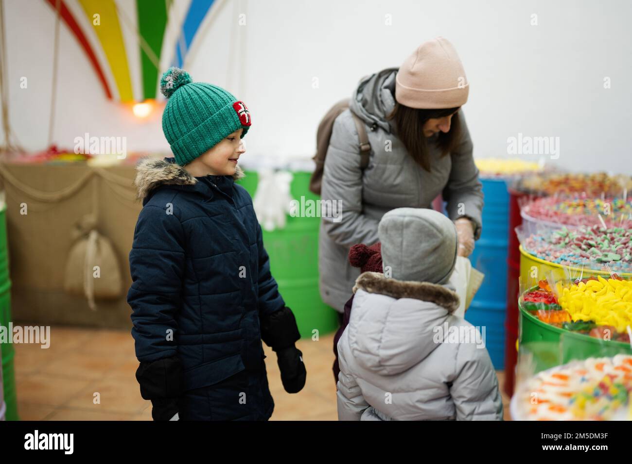 Happy little kids with mother in a candy store chooses sweets ...