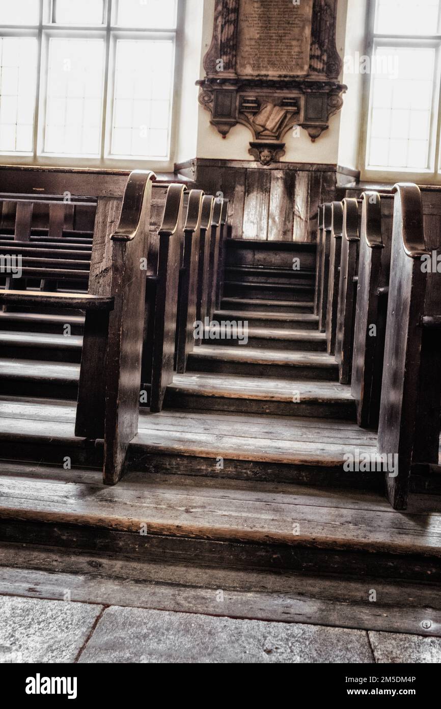 A vertical shot of wooden steps leading to old-fashioned pews in the ...