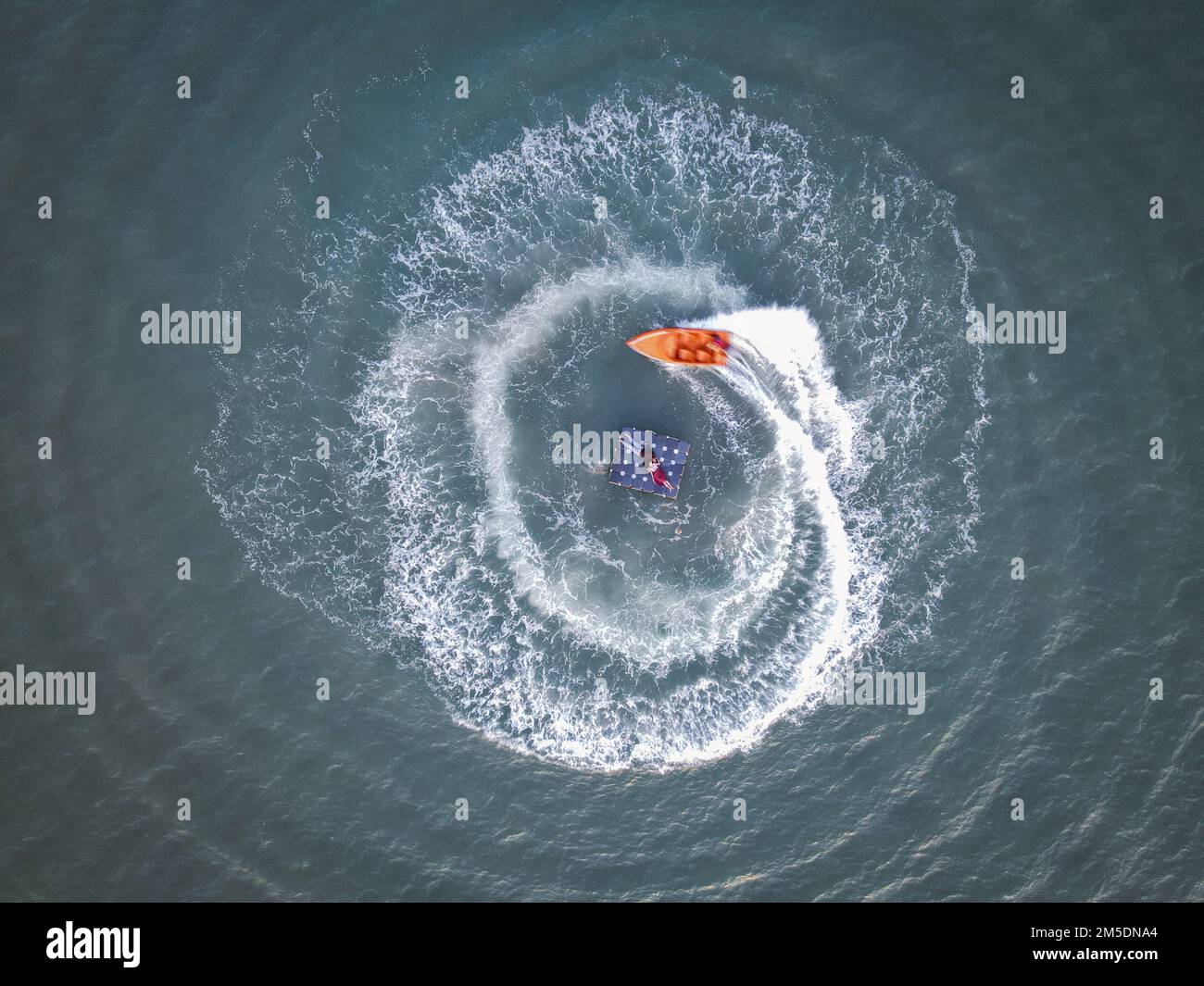 An aerial top view of a sea surface with a couple laying on a floating ...