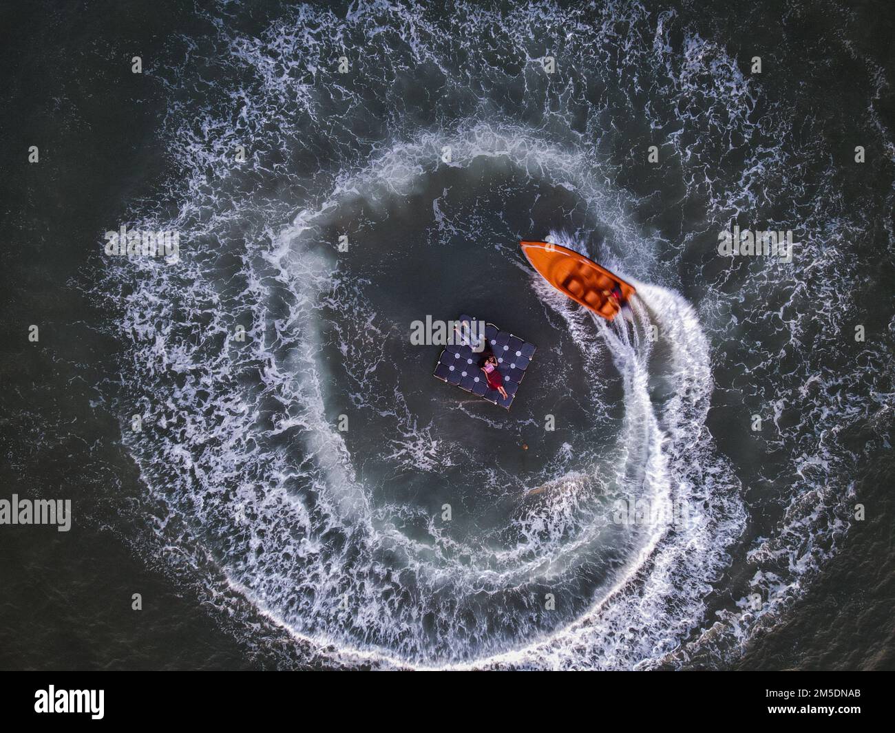 An aerial top view of a sea surface with a couple laying on a floating ...