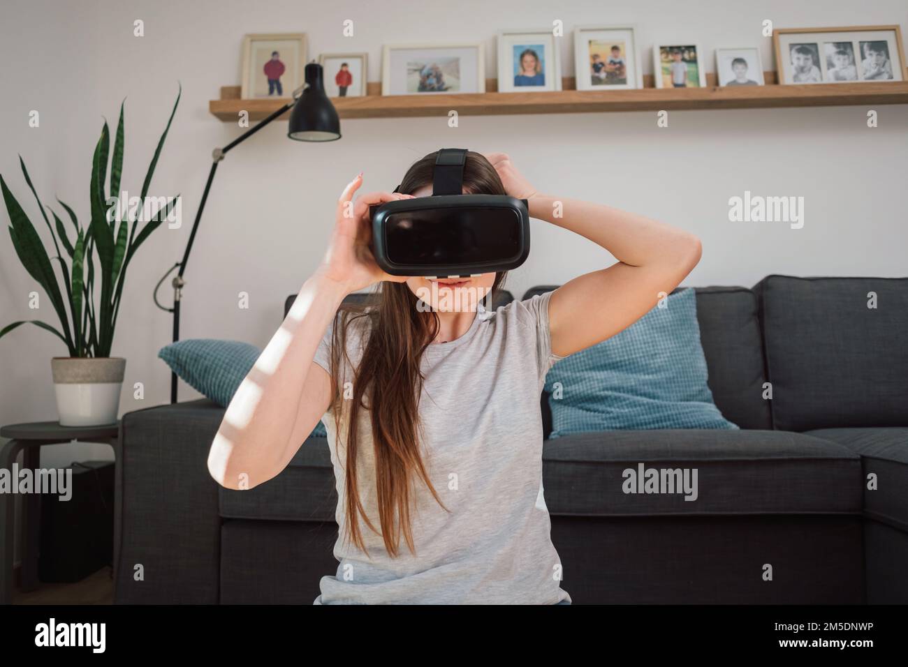 Young woman wearing virtual reality glasses, exploring the augmented world, interacting with the ...