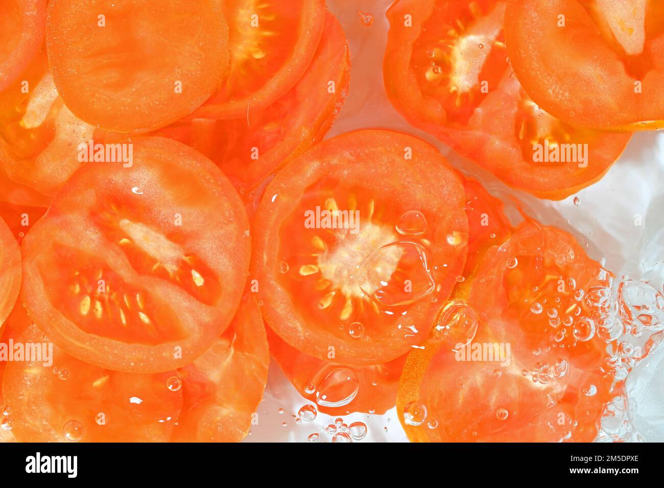 Tomato close-up in liquid with bubbles. Slices of red ripe tomato in ...