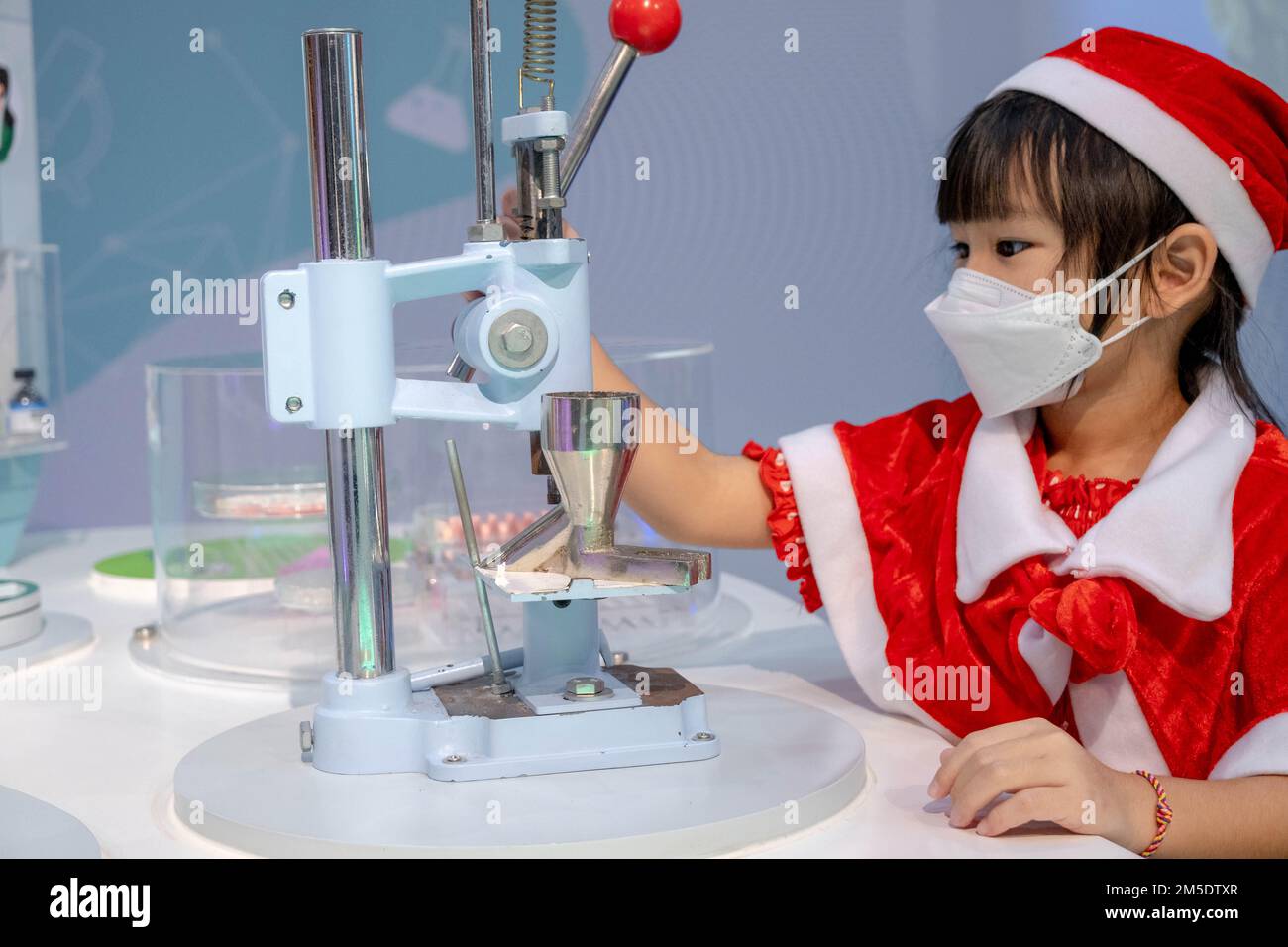 Cute little Asian girl in red santa dress looking at microscope in ...
