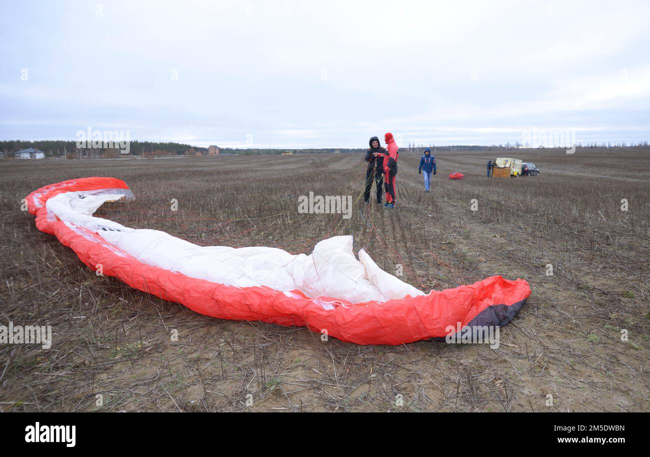 Powered paragliding. Men preparing the paramotor wing for flight in a ...