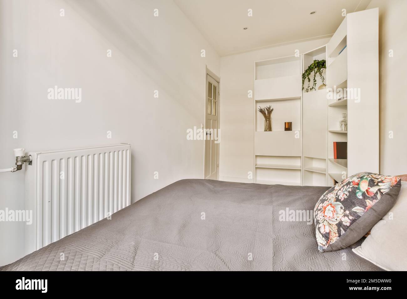 a bedroom with a bed and a radiaing unit in the photo is taken from an ...