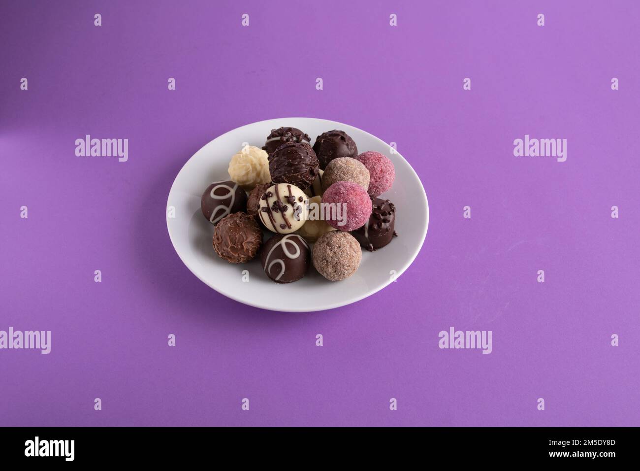 photo mix of chocolates on a plate in purple background Stock Photo - Alamy