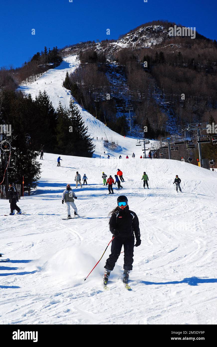 A young woman finishes her ski run on the slopes at the base of a ...