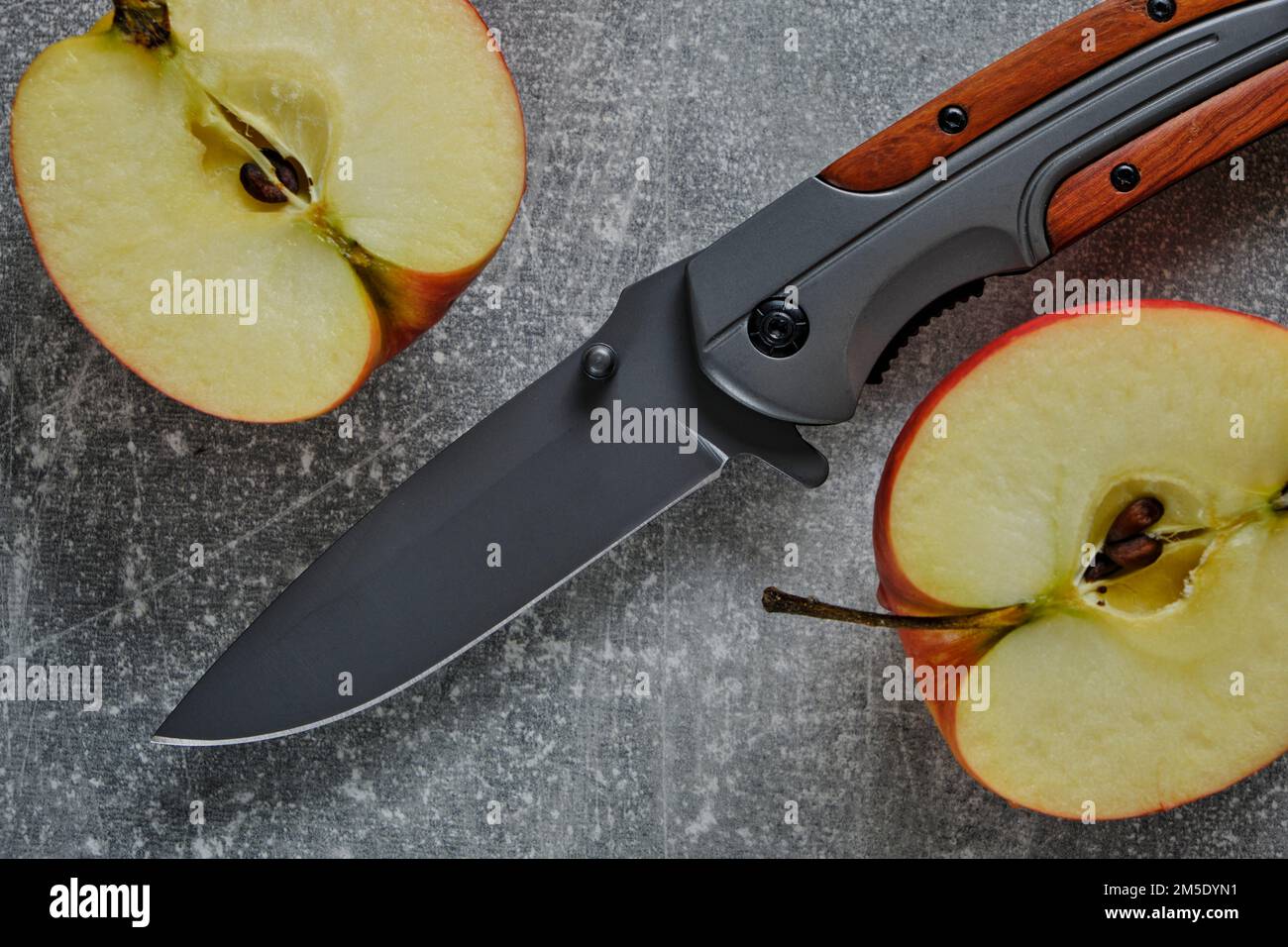Folding knife for survival and two halves of cut apple Stock Photo - Alamy