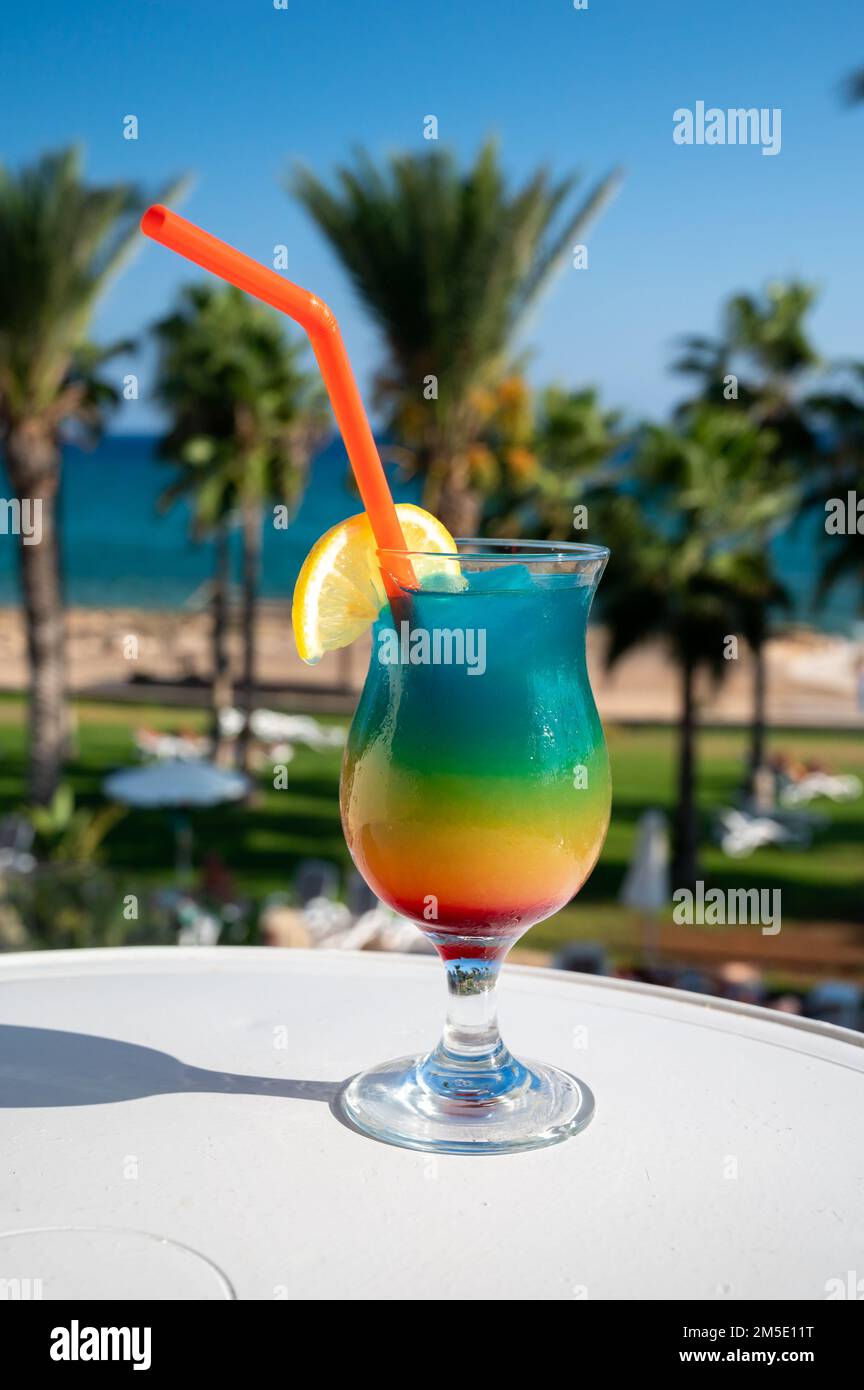 Colourful frozen Rainbow Paradise cocktail drink served in glass at ...