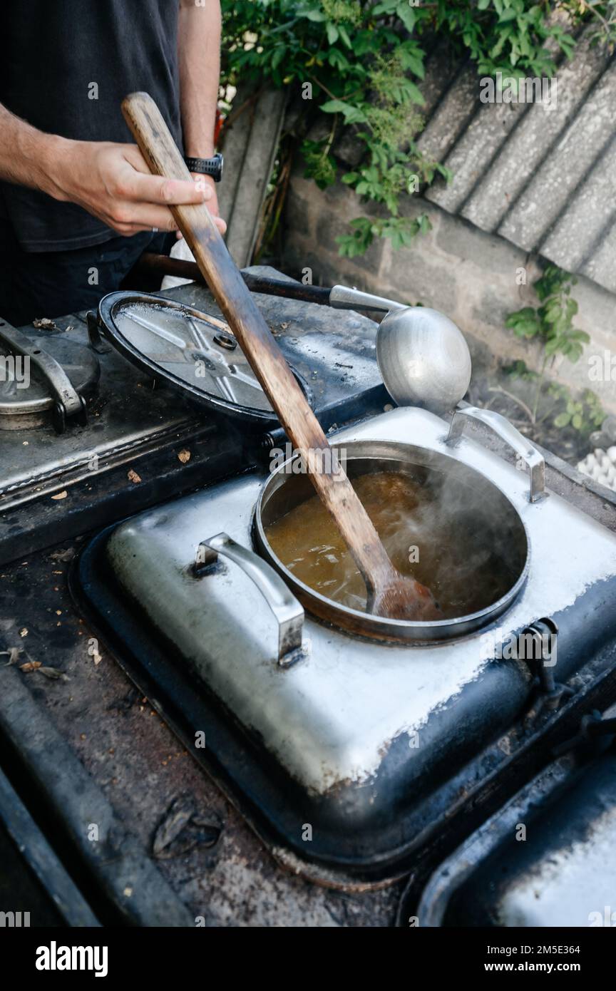 A man prepares lunch in a military field kitchen, a large wooden spatula for stirring food Stock ...