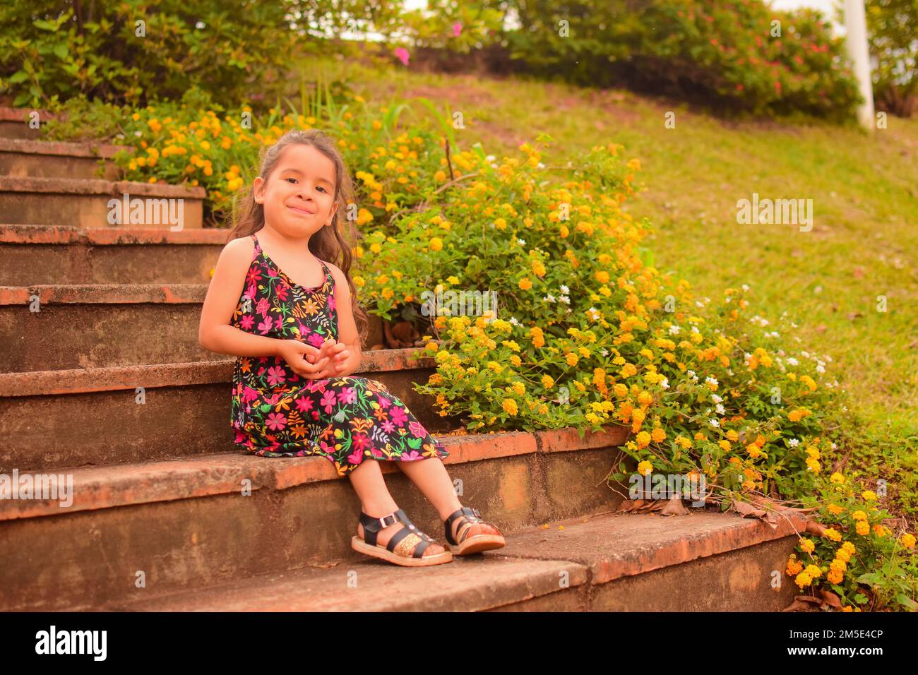 A little Spanish kid with a cute face posing for a picture in a park ...
