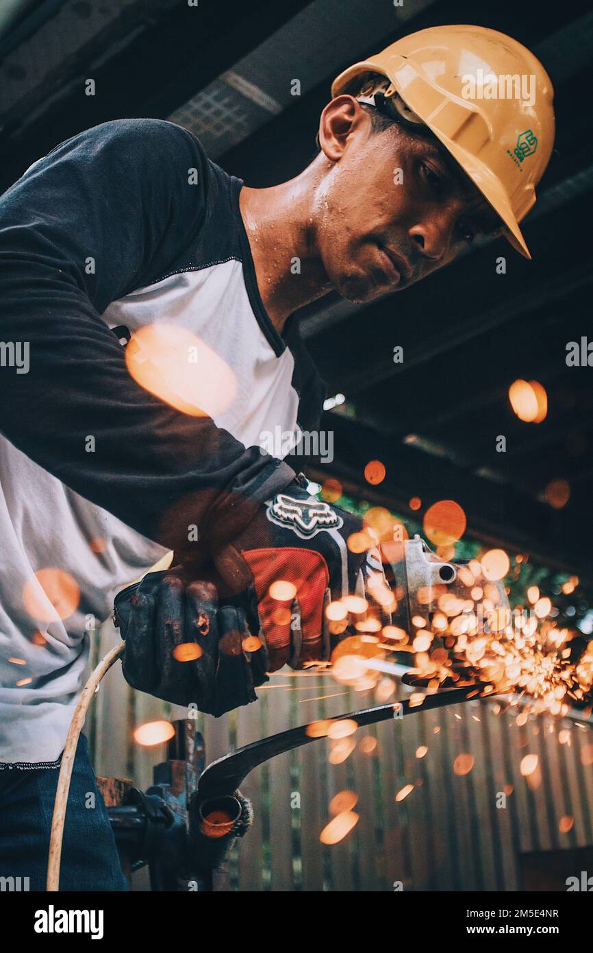 A vertical portrait of a man welding with opened eyes while wearing a ...