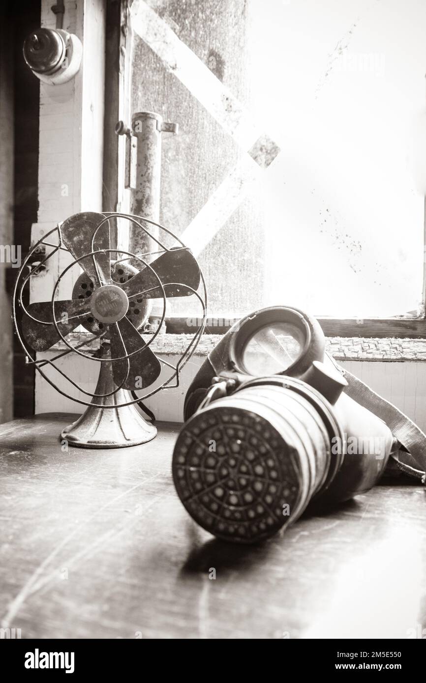 A vertical shot of a vintage electric fan and World War II gas mask ...