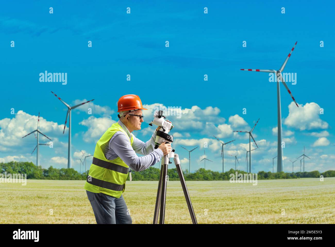 Geodetic surveyor with a measuring equipment working on a wind farm ...