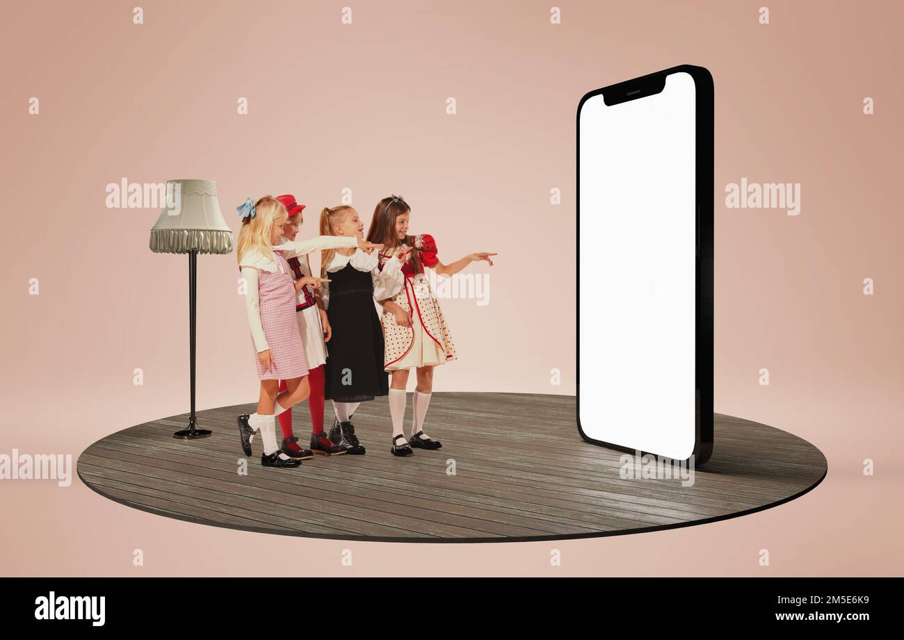 Stylish, cute, little girls, children looking on huge 3D model of phone ...