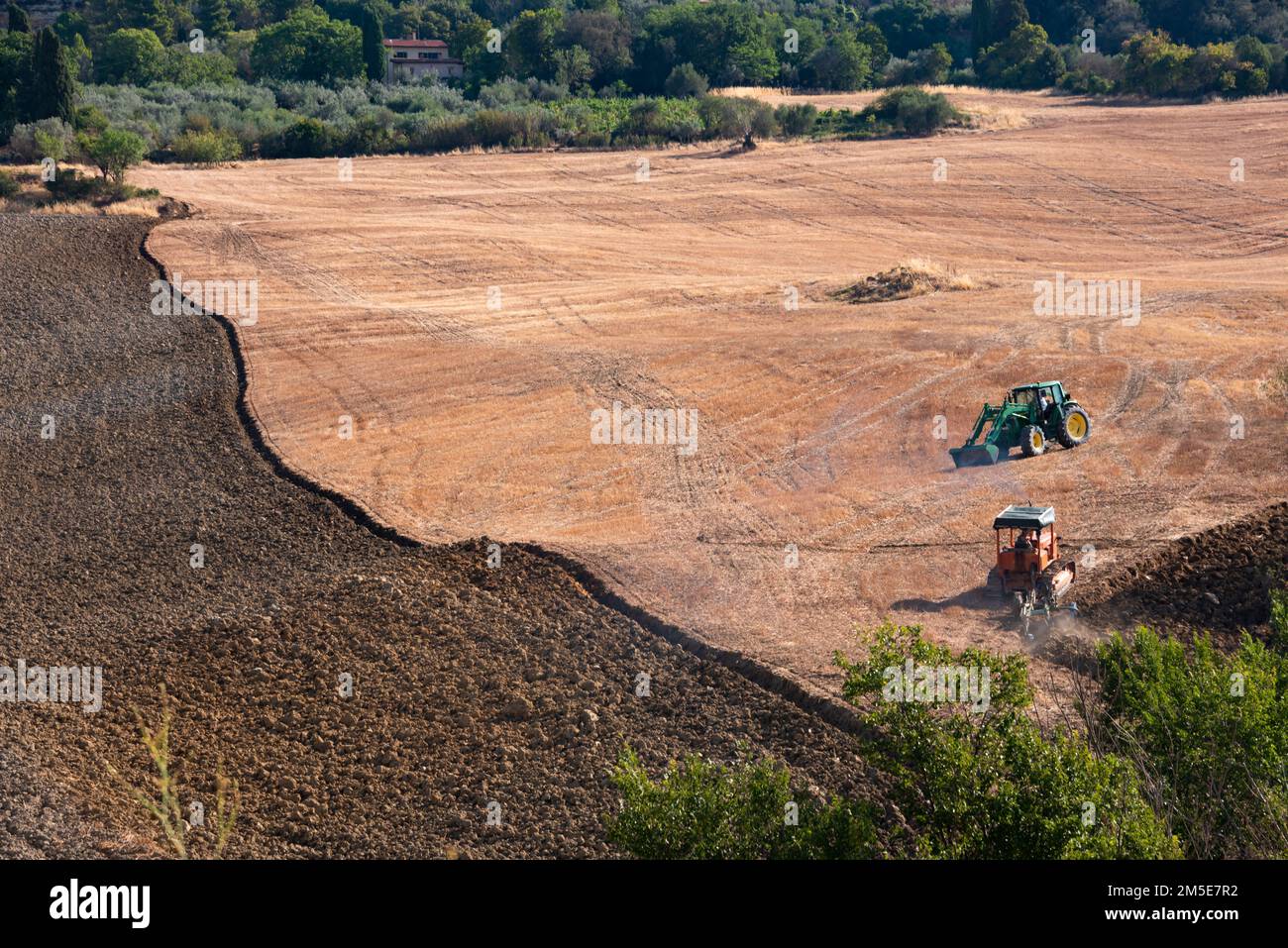 Tractor working on farming lands, countryside landscape in Tuscany ...