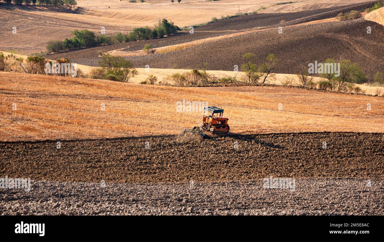 Tractor working on farming lands, countryside landscape in Tuscany ...