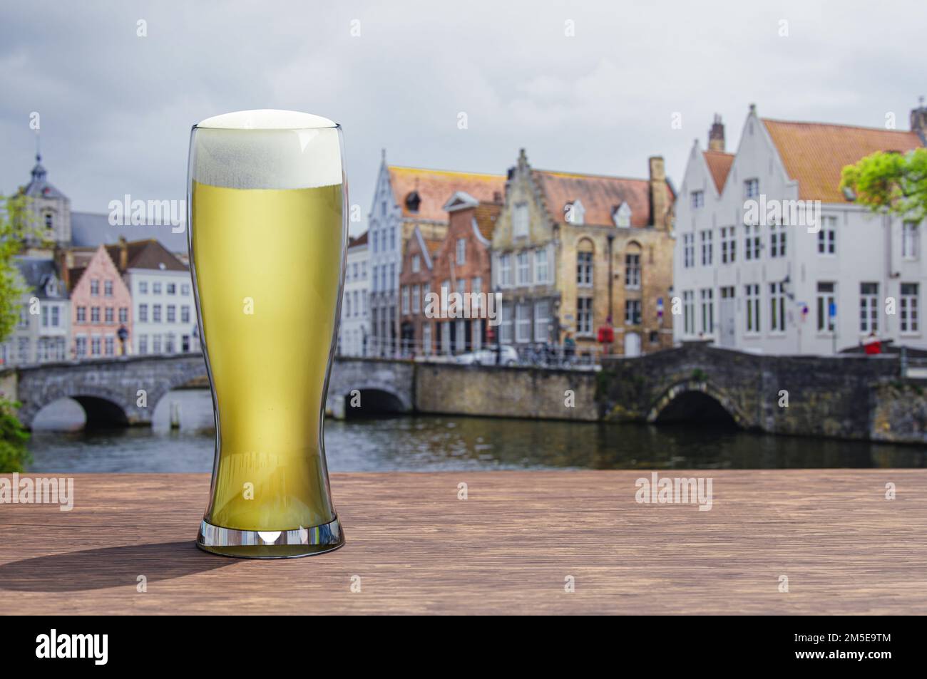Glass of light beer on wooden table with view of canal and street in ...