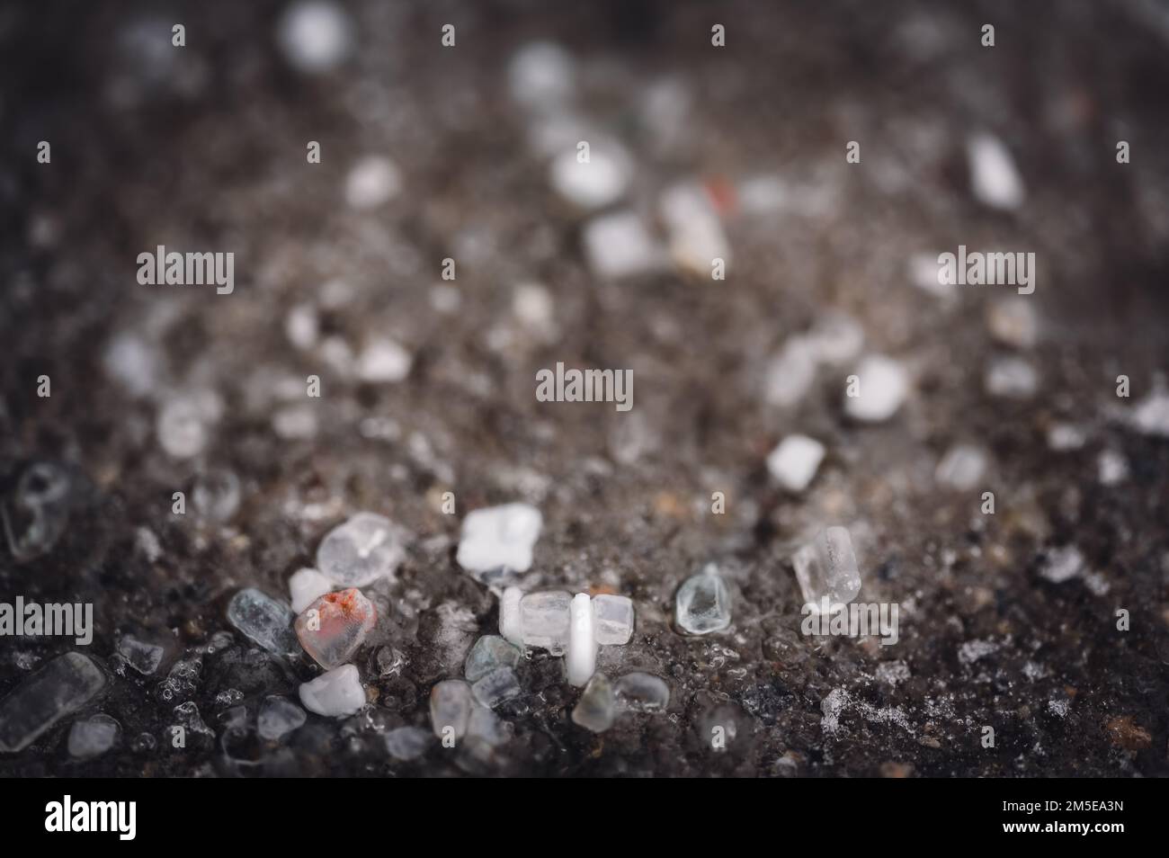 macro ground level closeup view of rock salt ice-melt on concrete with ...