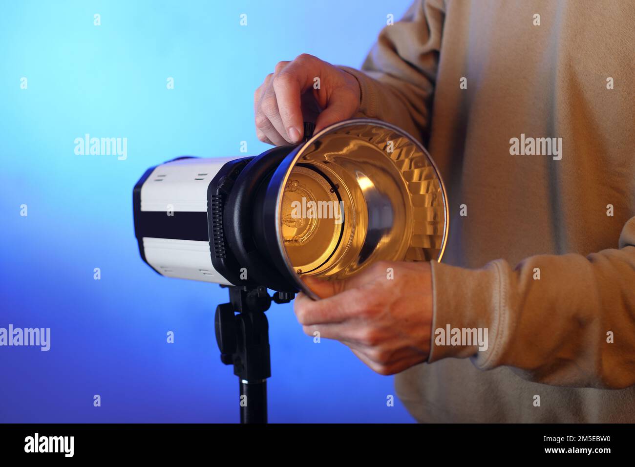person taking off flash shade on blue background Stock Photo - Alamy