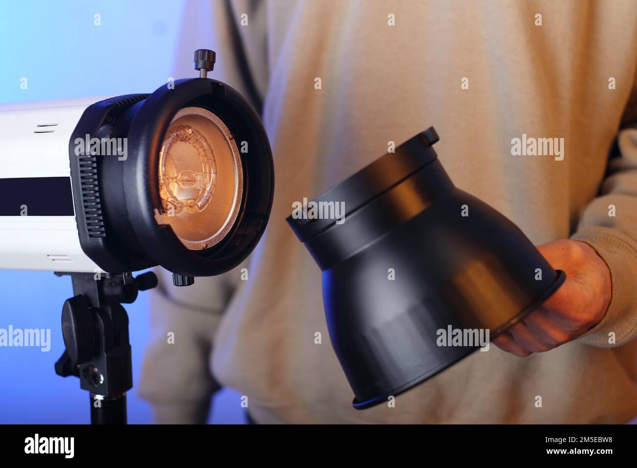 person taking off flash shade on blue background Stock Photo - Alamy