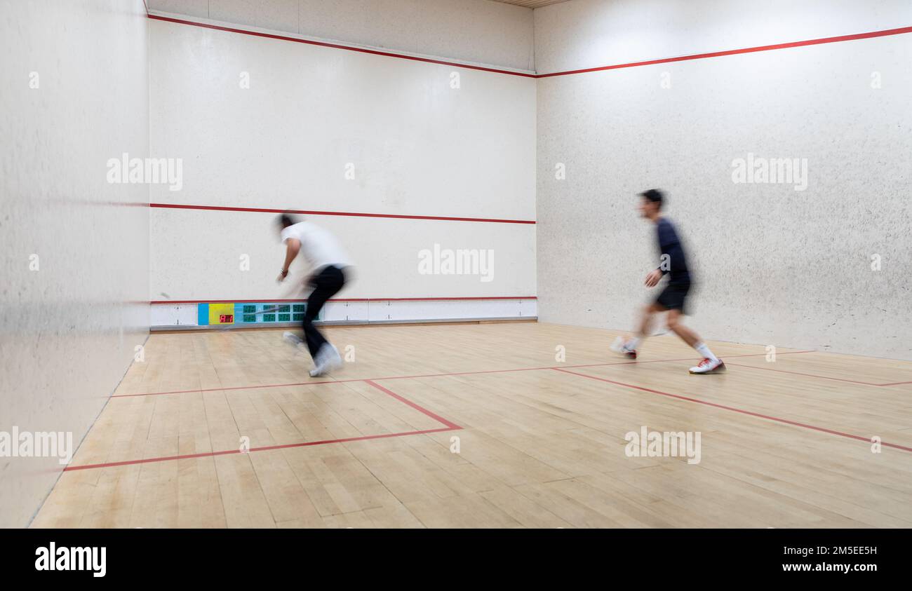Squash players in action on a squash court (motion blurred image; color ...