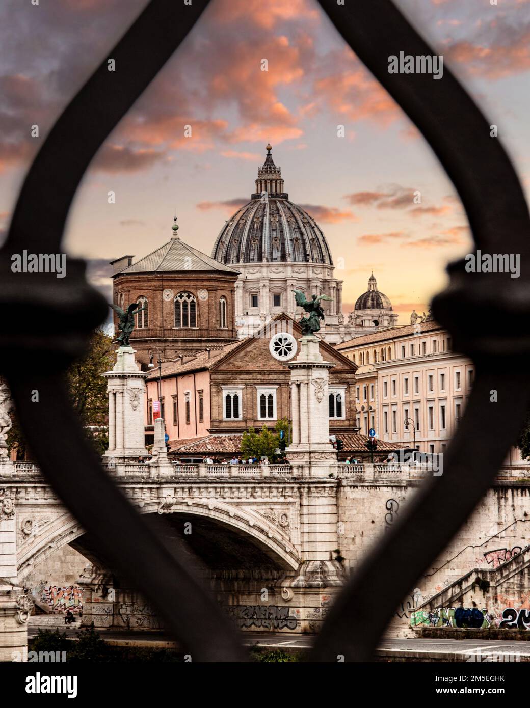 The vertical view from a fence to the St. Peter's Basilica at sunset ...