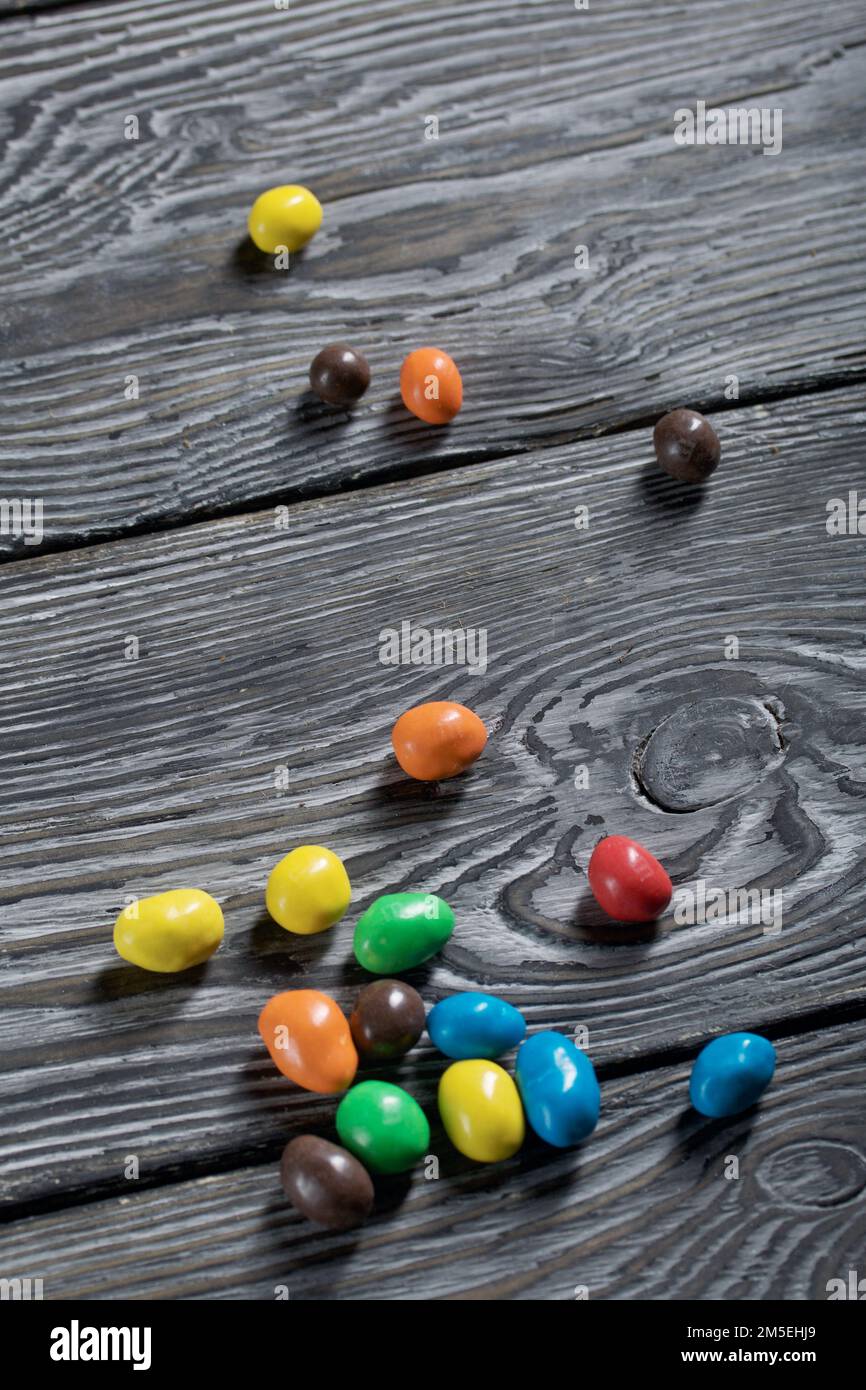 Chocolate candy in multi-colored glaze. Scattered on black pine boards ...