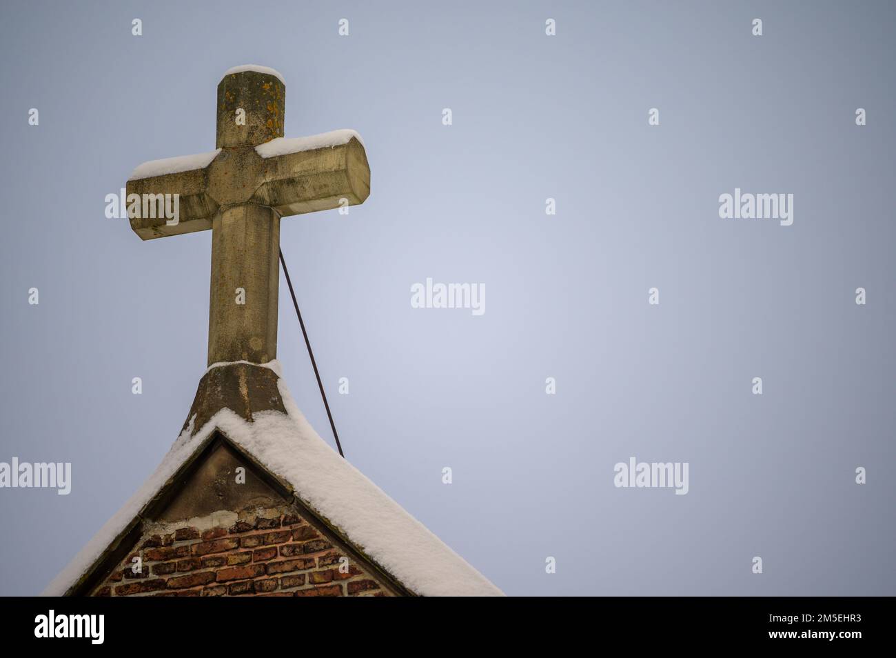 A concrete cross on top of a brick church roof covered in snow Stock ...