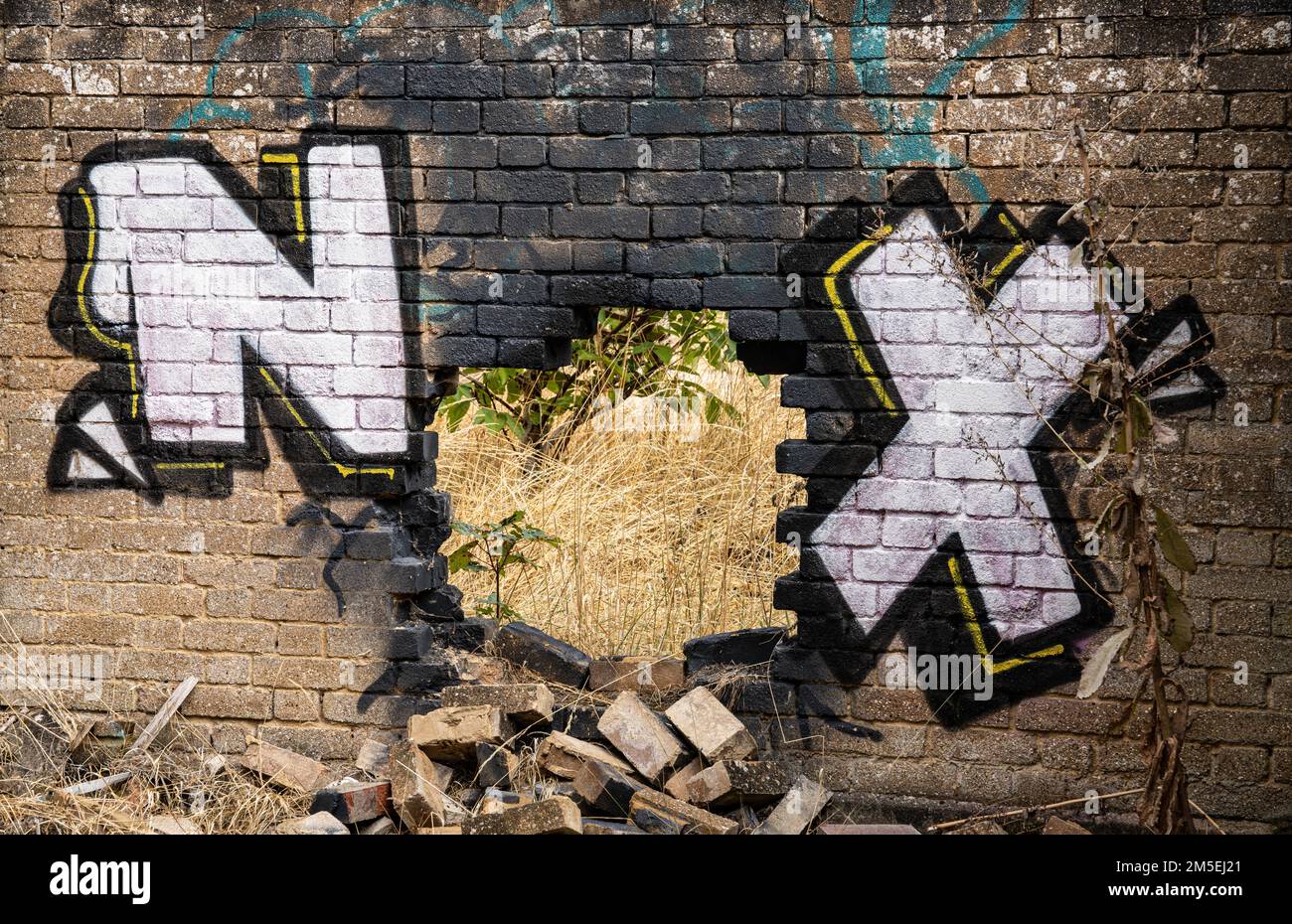 Hole in brick wall with grafitti lettering Stock Photo - Alamy