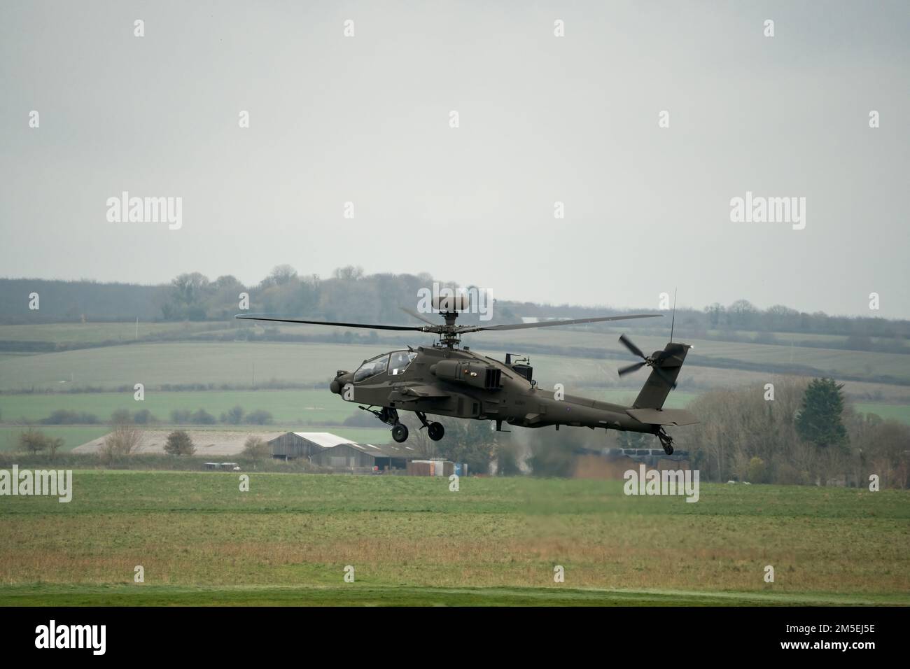 A dark gray army attack helicopter in flight during the daytime Stock Photo - Alamy