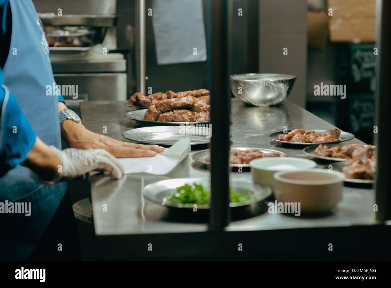 A view through a window of a chef preparing a meal with meat Stock ...