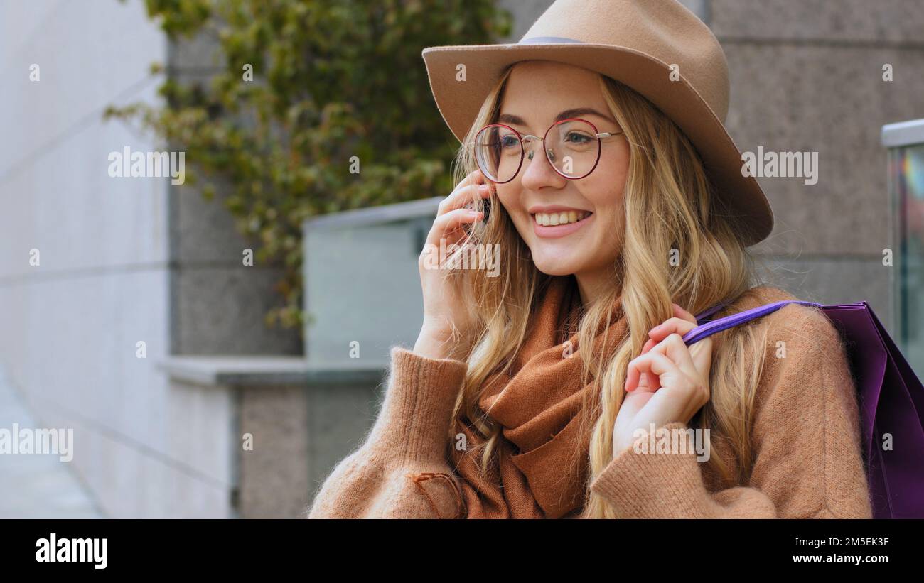 Portrait girl in hat and glasses with shopping bags outdoors answer ...