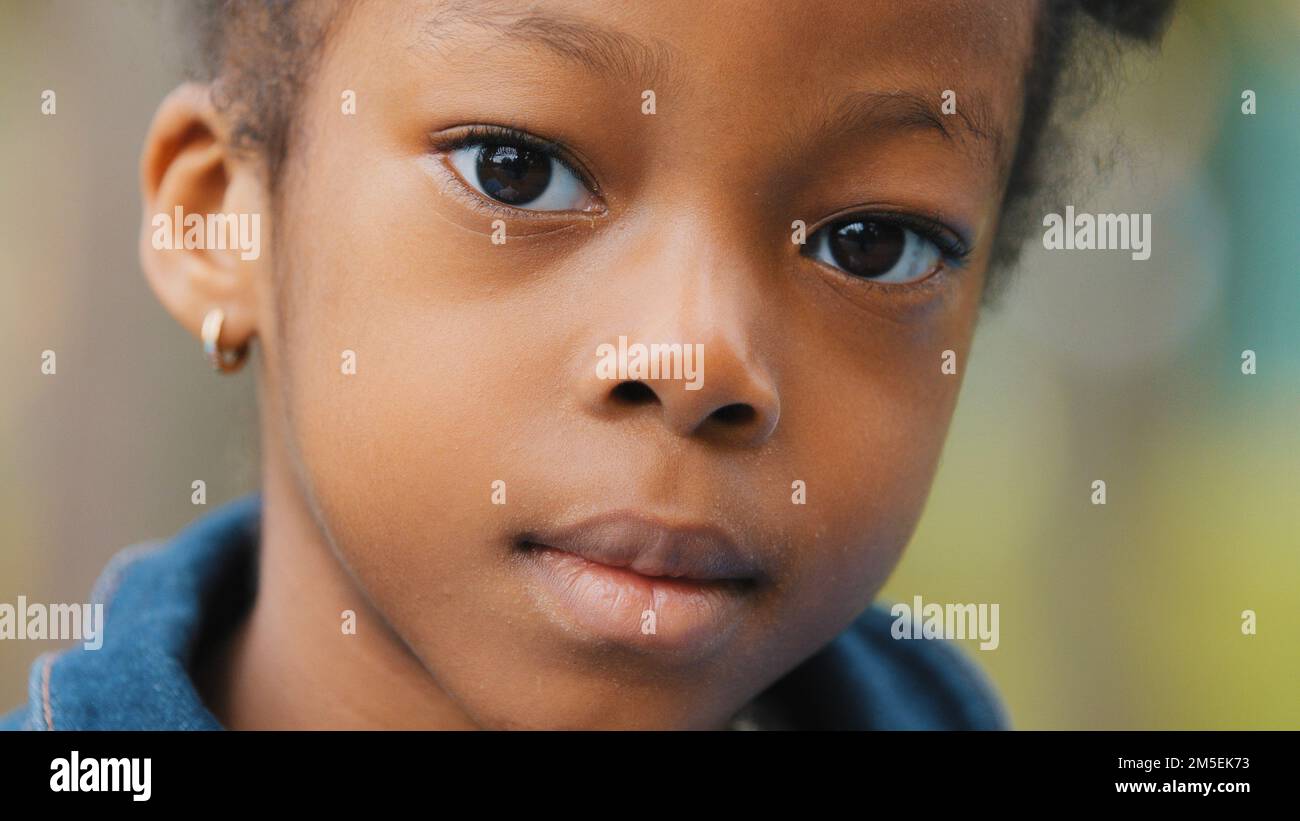 Close-up little beautiful afro girl in park schoolgirl seriously ...