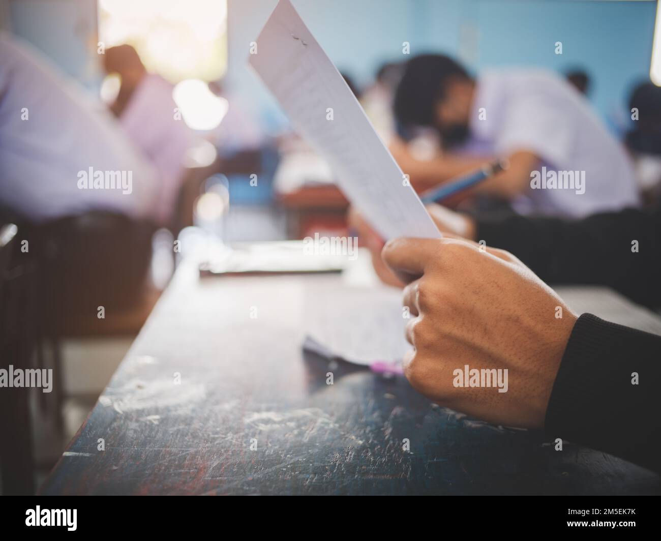 University student holding pen or pencil writing on paper answer sheet ...