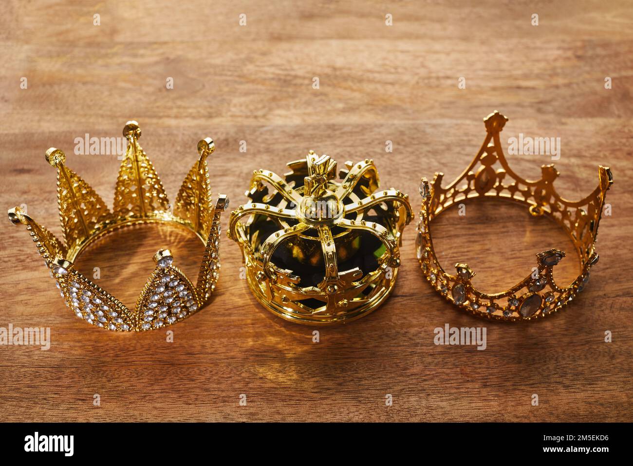 Happy Epiphany day. Three gold crowns on wooden background, symbol of ...