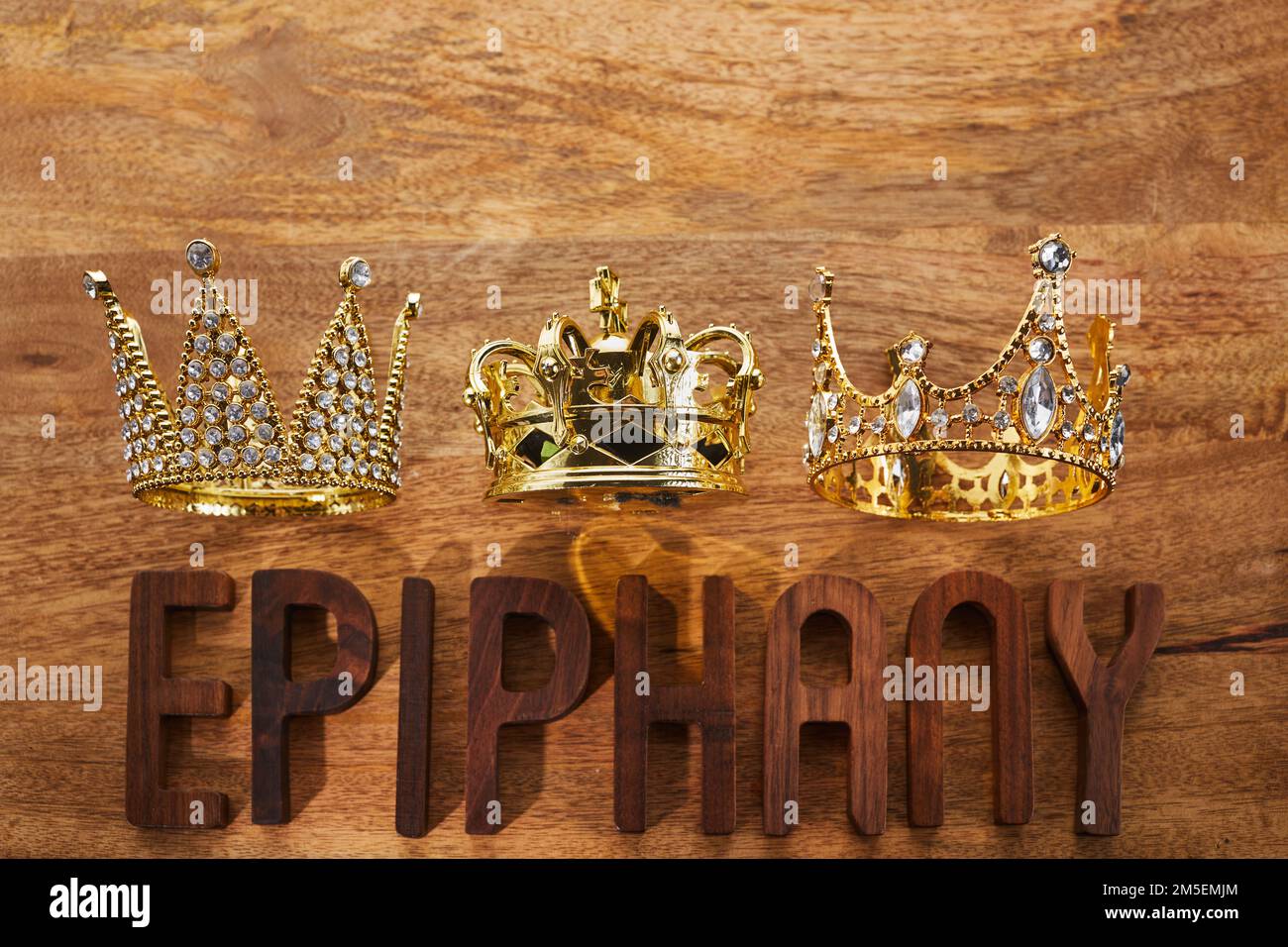 Happy Epiphany day. Three gold crowns on wooden background, symbol of ...