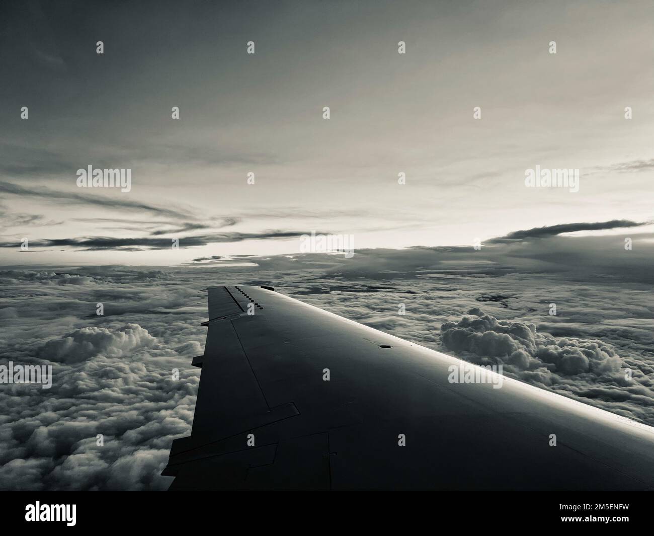 A dark shot of the wing of a plane in the clouds during its flight ...