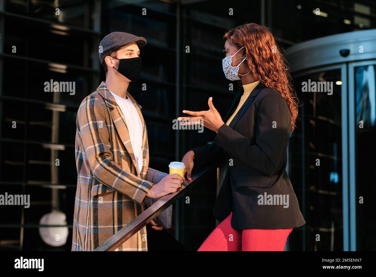 Two business people with face mask talking outside office building ...