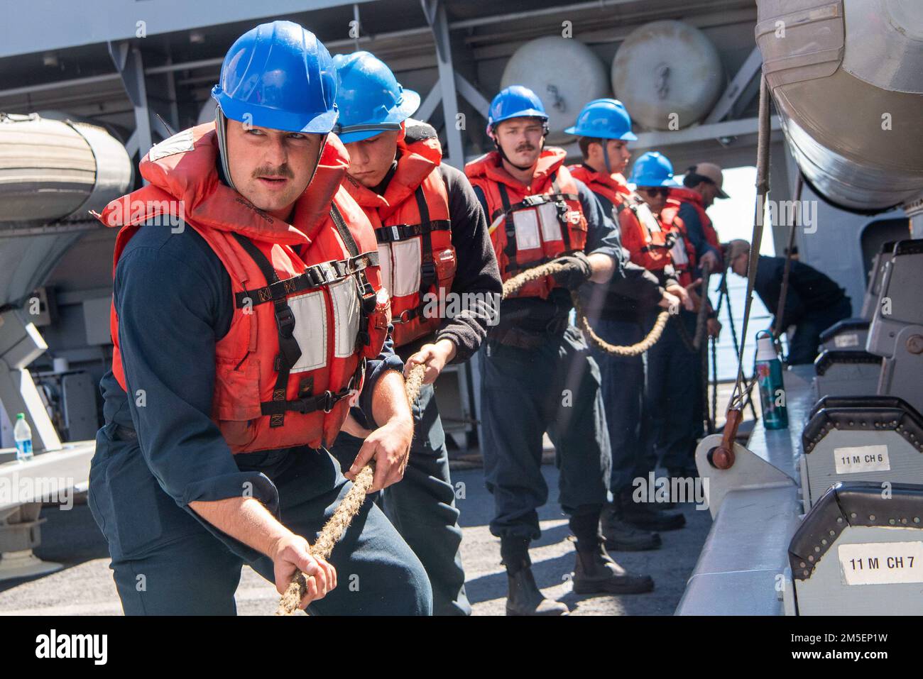 Sailors aboard amphibious transport dock USS Anchorage (LPD 23) heave ...