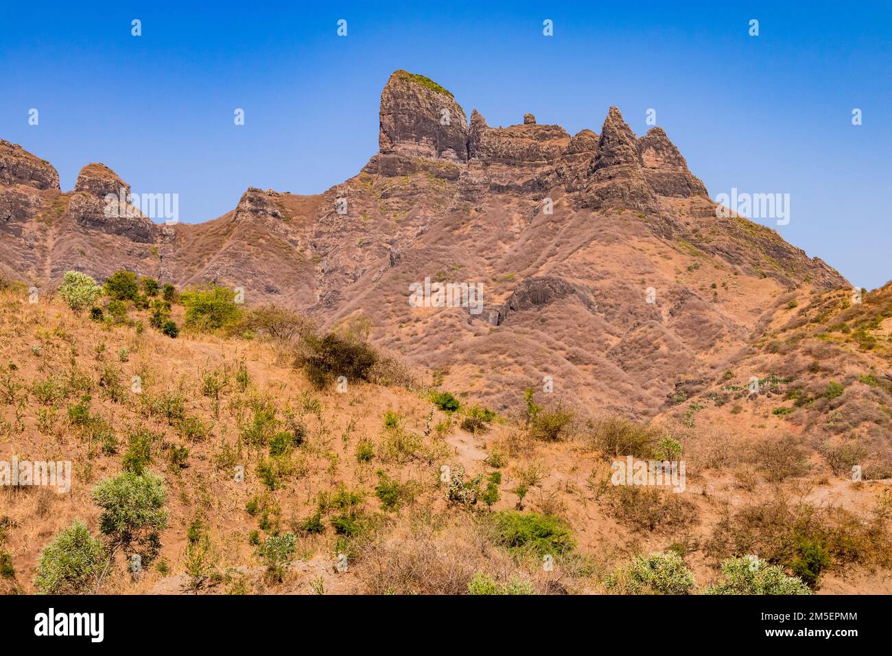 A striking mountain formation with rocks, grasses and shrubs in the ...