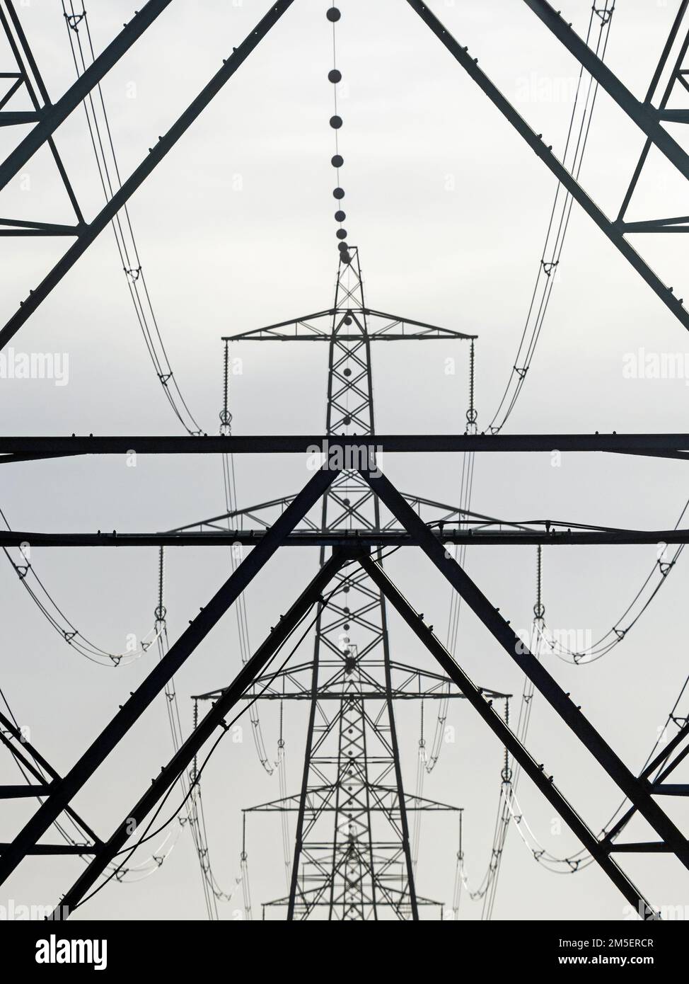 View down a line of electricity pylons in the fens, Norfolk, England ...